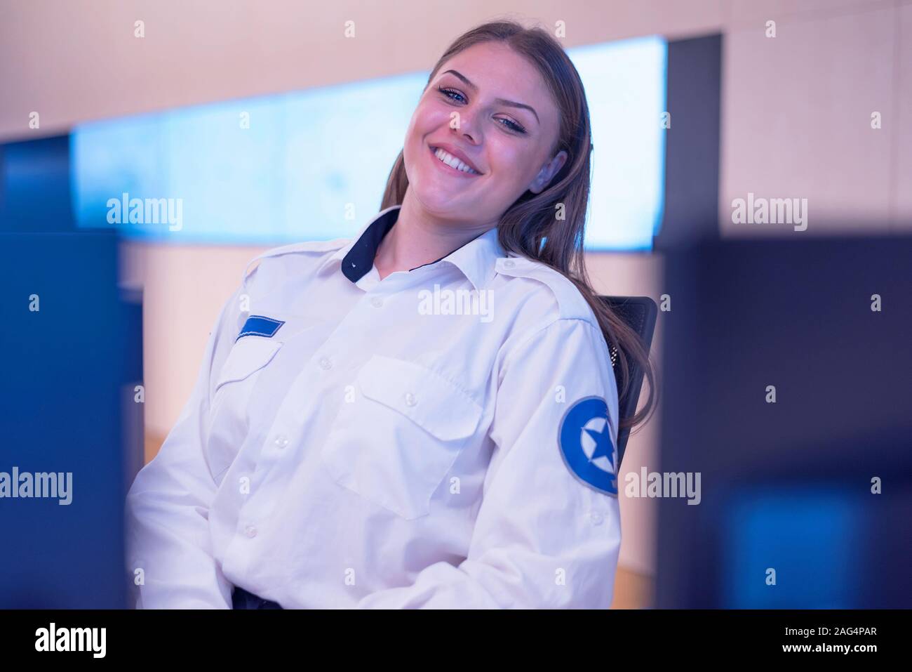 Female security guard working on computers while sitting in the main ...