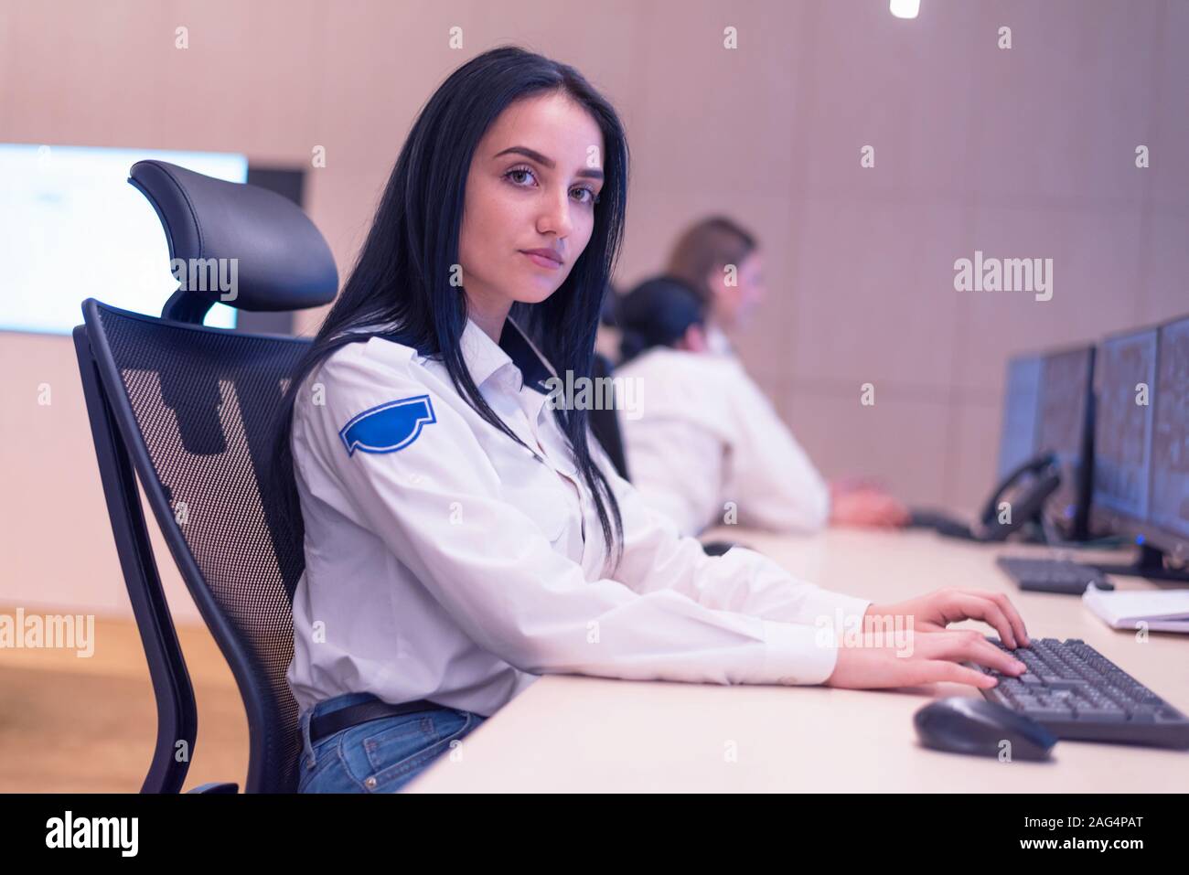 Female security guard working on computers while sitting in the main ...