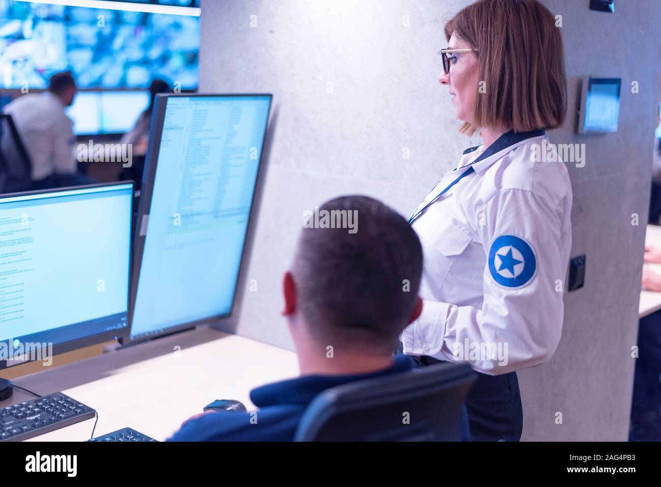 Two security guards working on computers while sitting in the main ...
