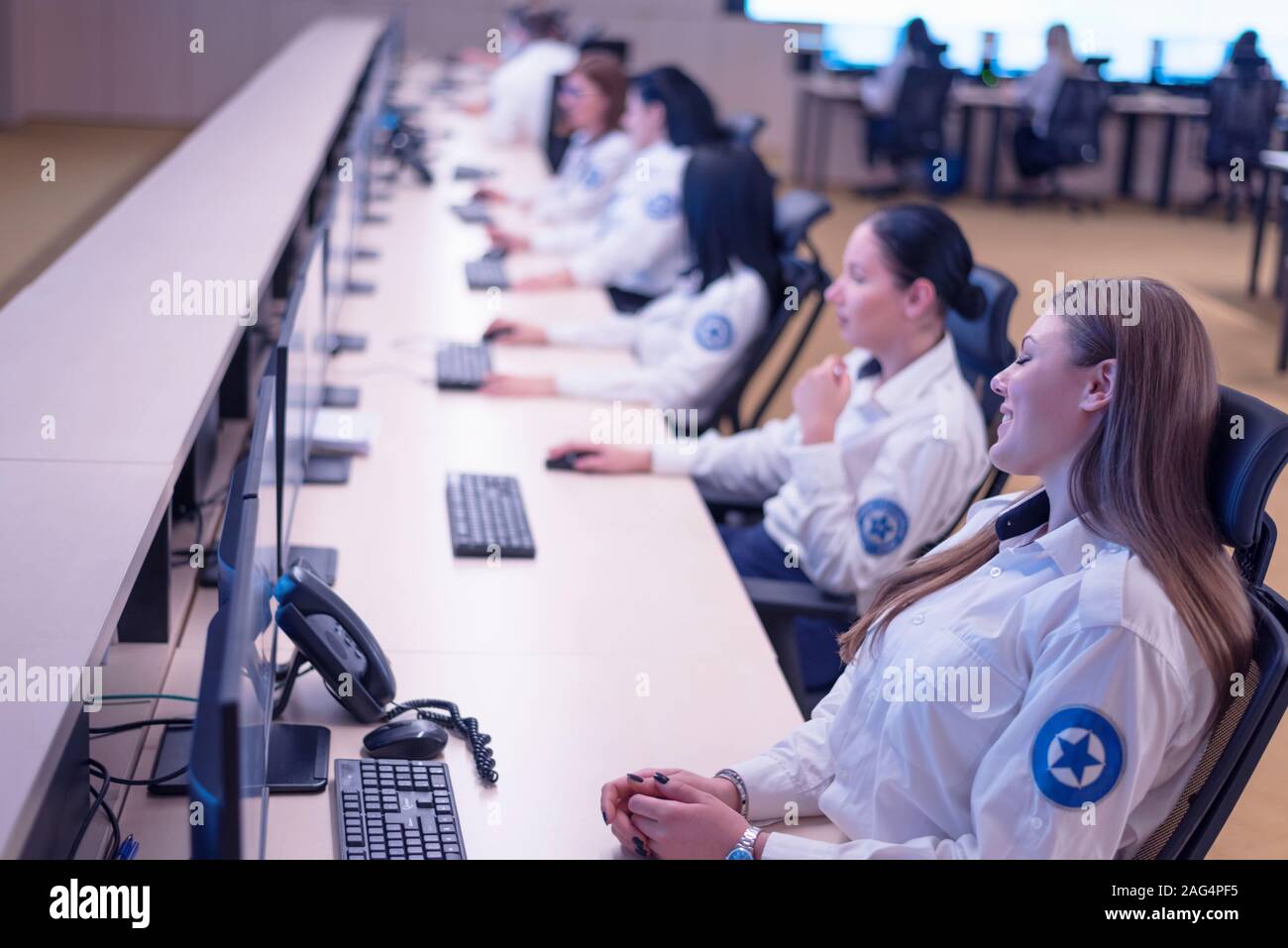 Group of security guards working on computers while sitting in the main ...