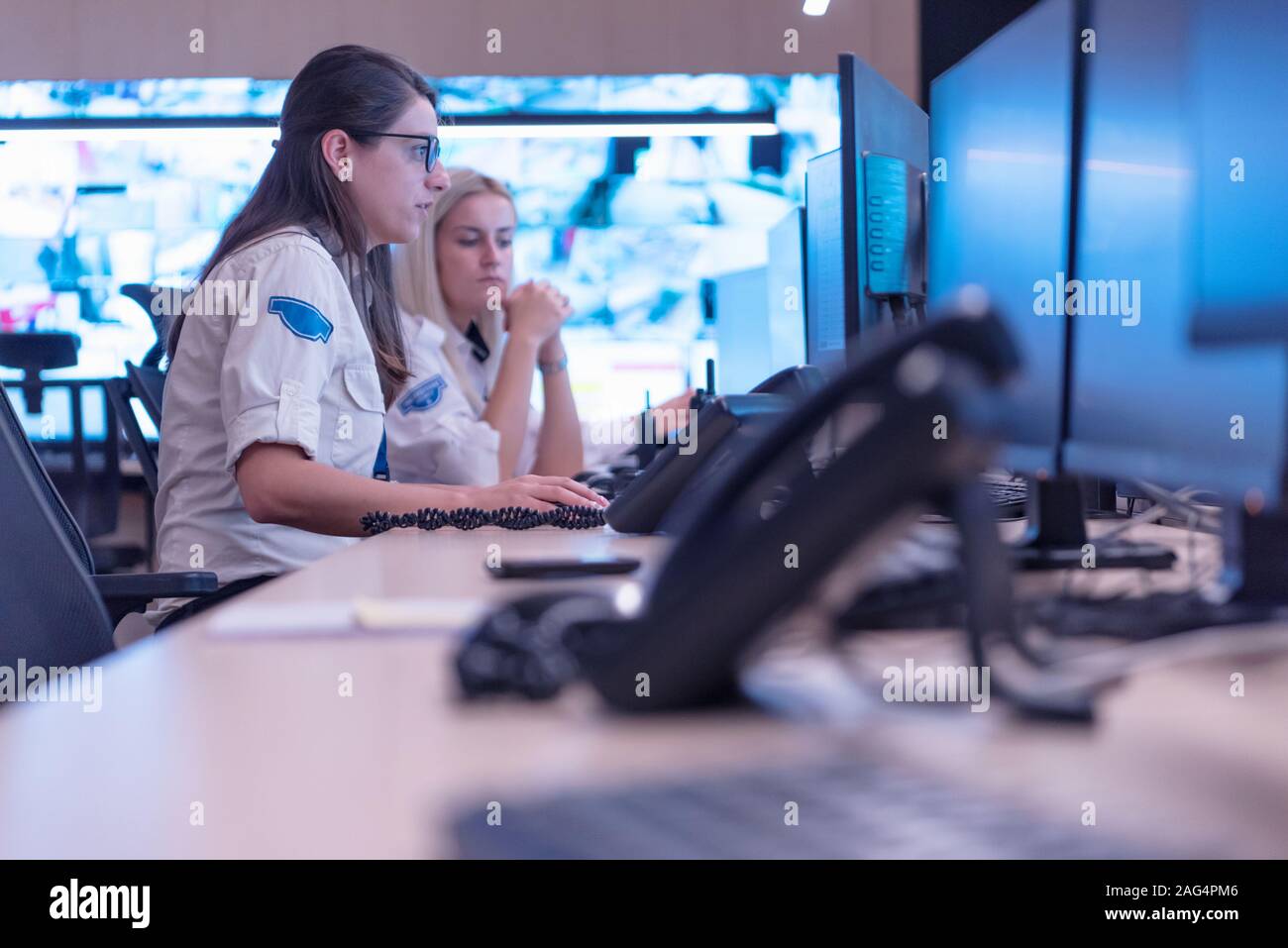 Group of security guards working on computers while sitting in the main ...