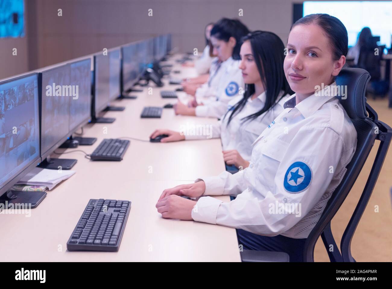 Group of security guards working on computers while sitting in the main ...