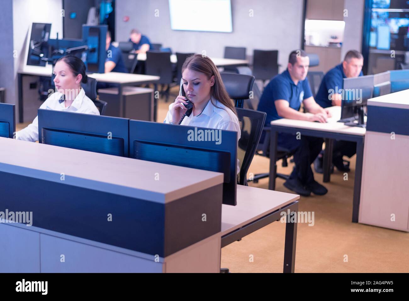 Group of security guards working on computers while sitting in the main ...