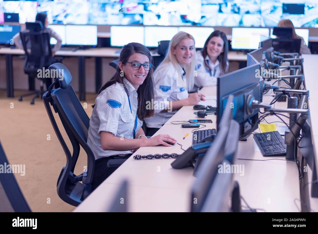 Group of security guards working on computers while sitting in the main ...