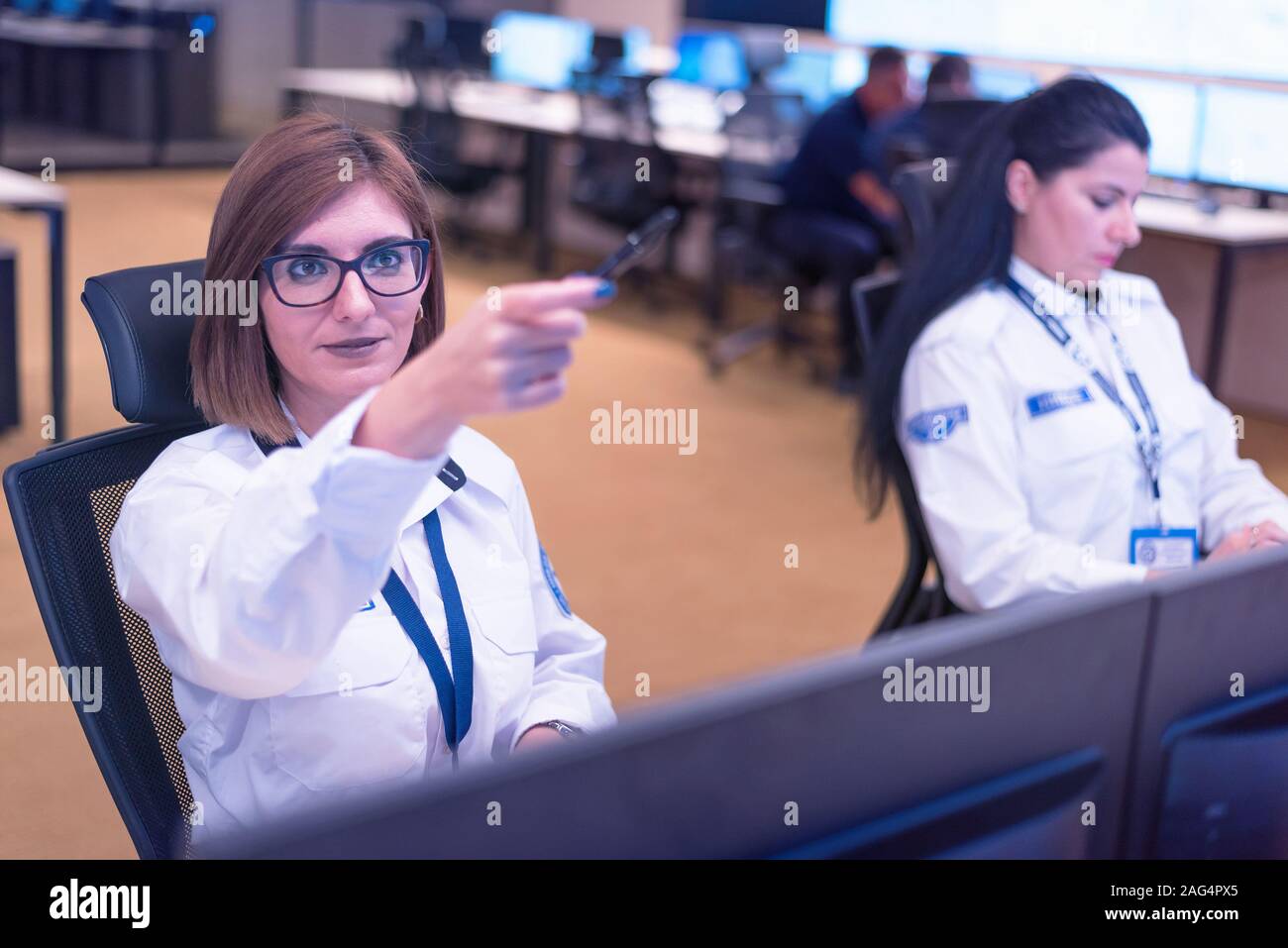 Group of security guards working on computers while sitting in the main ...