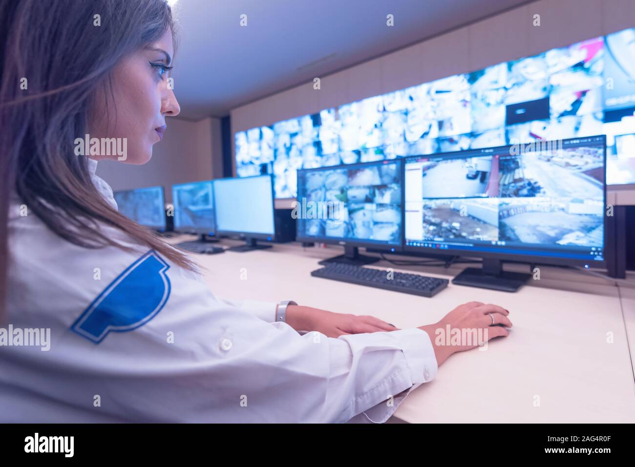Female security guard working on computers while sitting in the main ...