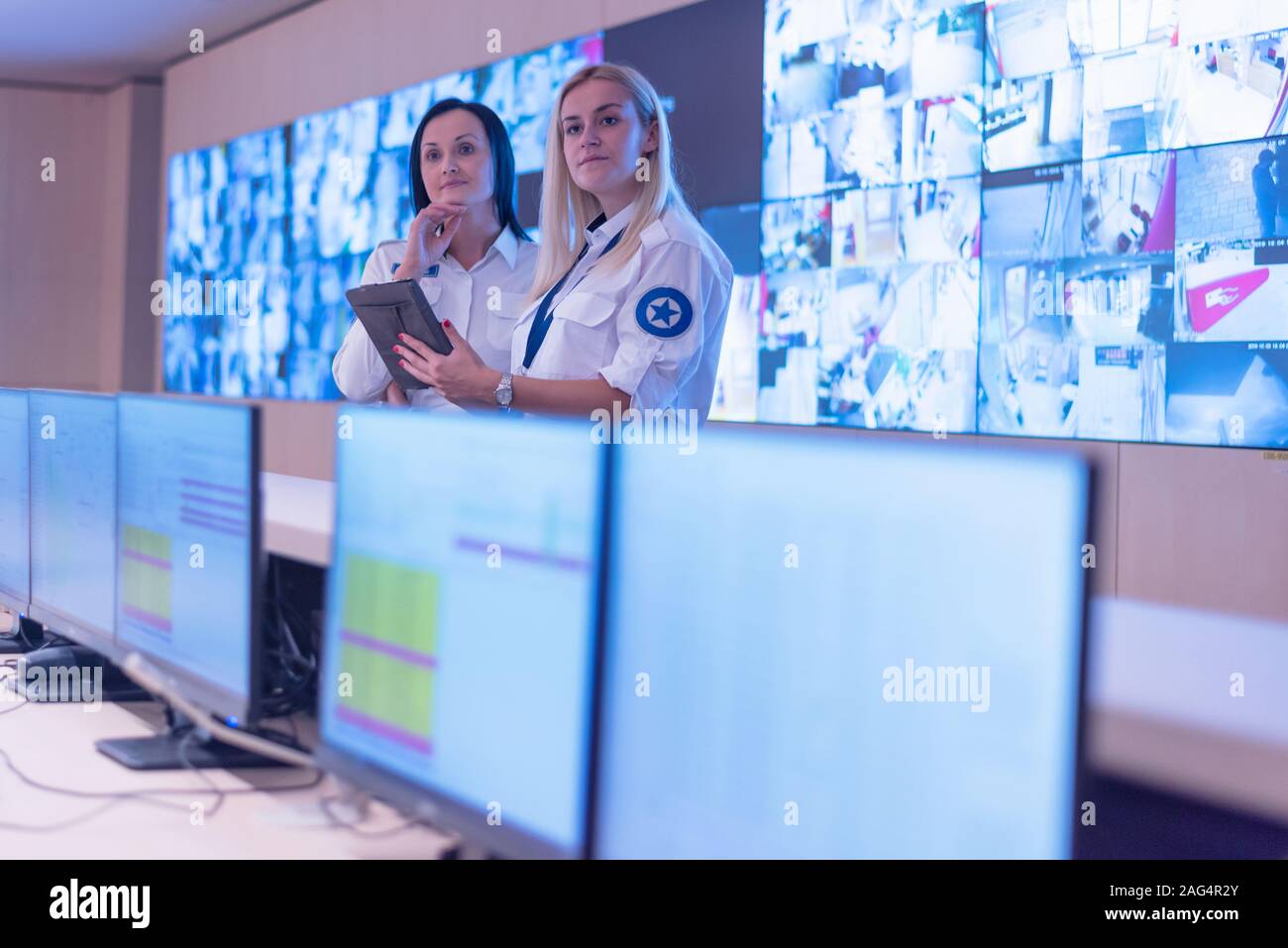 Two security guards working on computers while sitting in the main ...