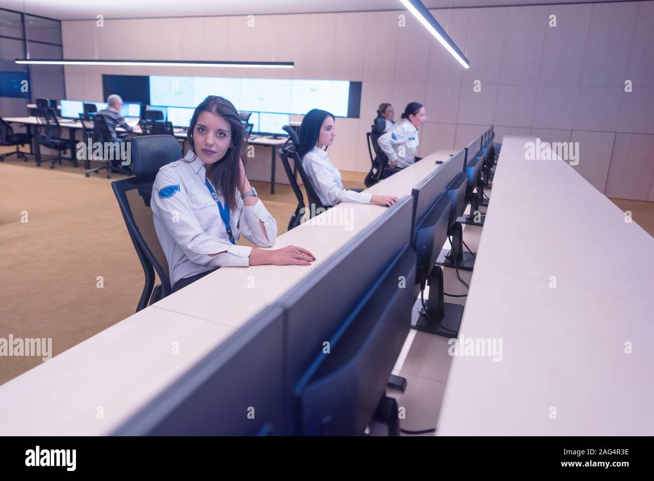 Group of security guards working on computers while sitting in the main ...