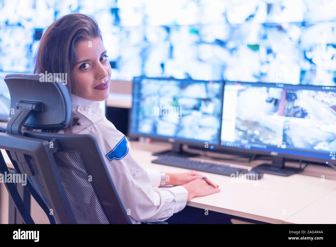 Female security guard working on computers while sitting in the main ...