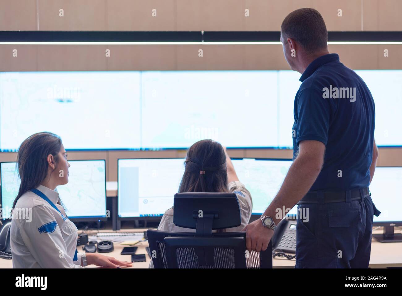 Group of security guards working on computers while sitting in the main ...