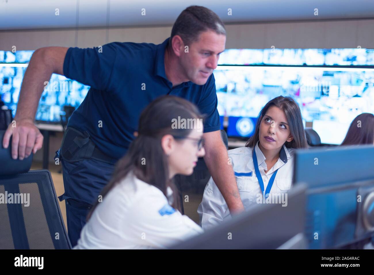 Group of security guards working on computers while sitting in the main ...