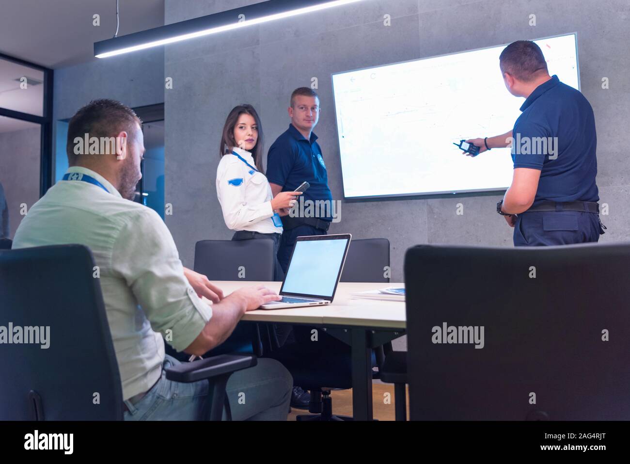 Group of security guards working on computers while sitting in the main ...