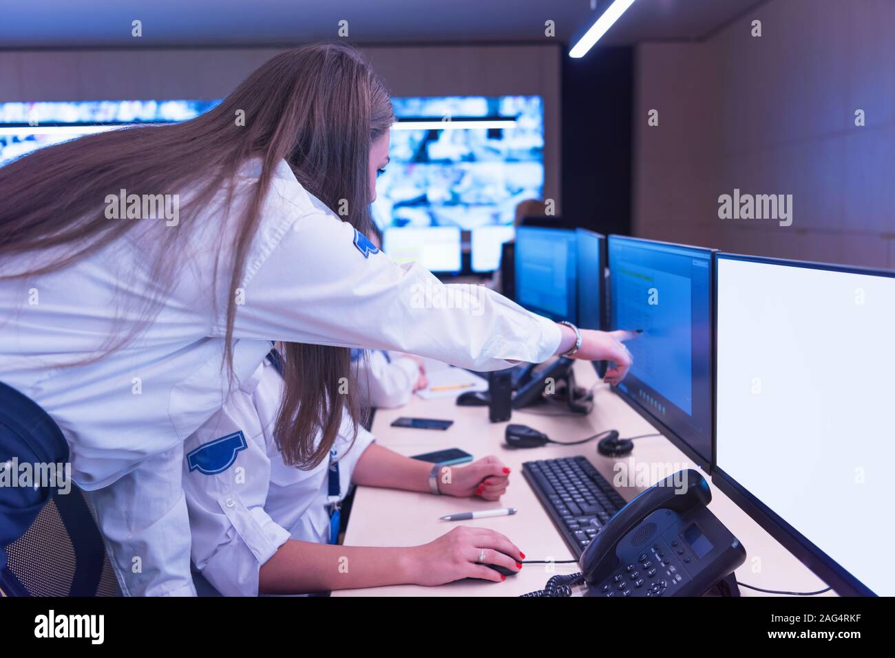 Group of security guards working on computers while sitting in the main ...