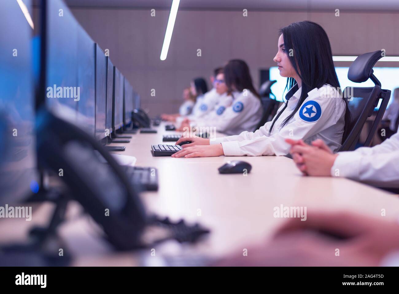 Group of security guards working on computers while sitting in the main ...