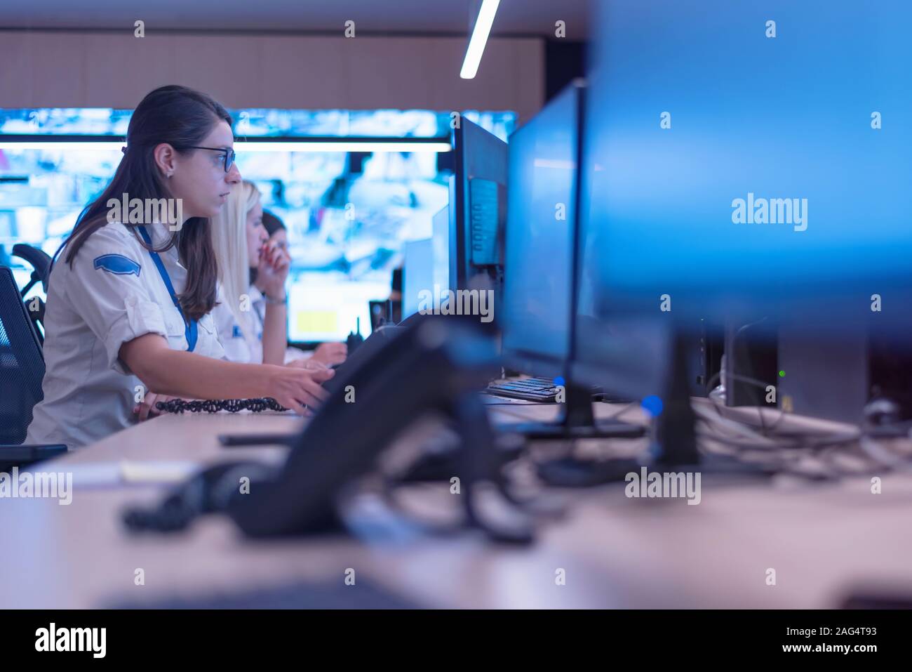 Group of security guards working on computers while sitting in the main ...