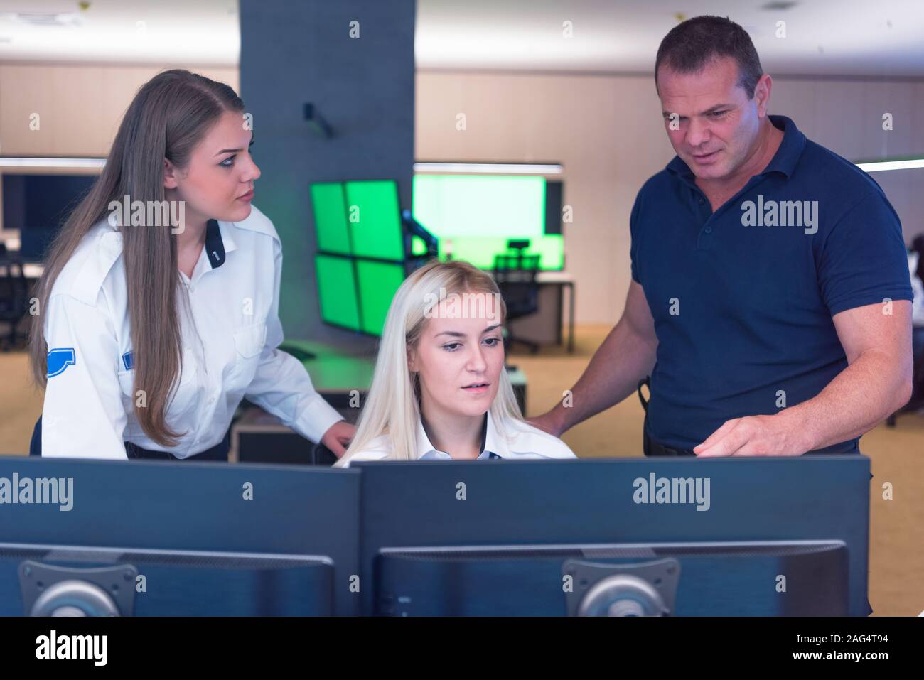 Group of security guards working on computers while sitting in the main ...