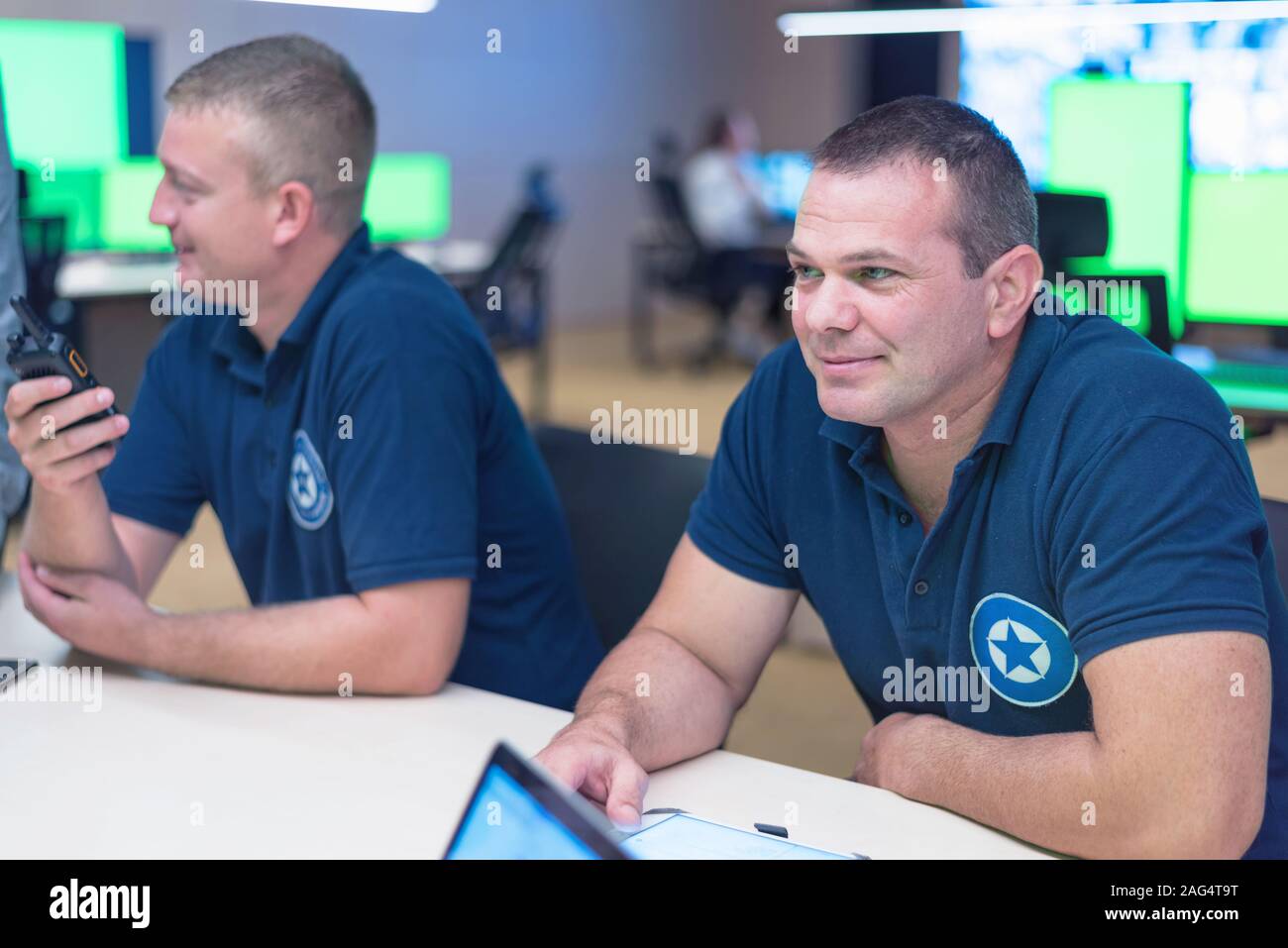 Group of security guards working on computers while sitting in the main ...