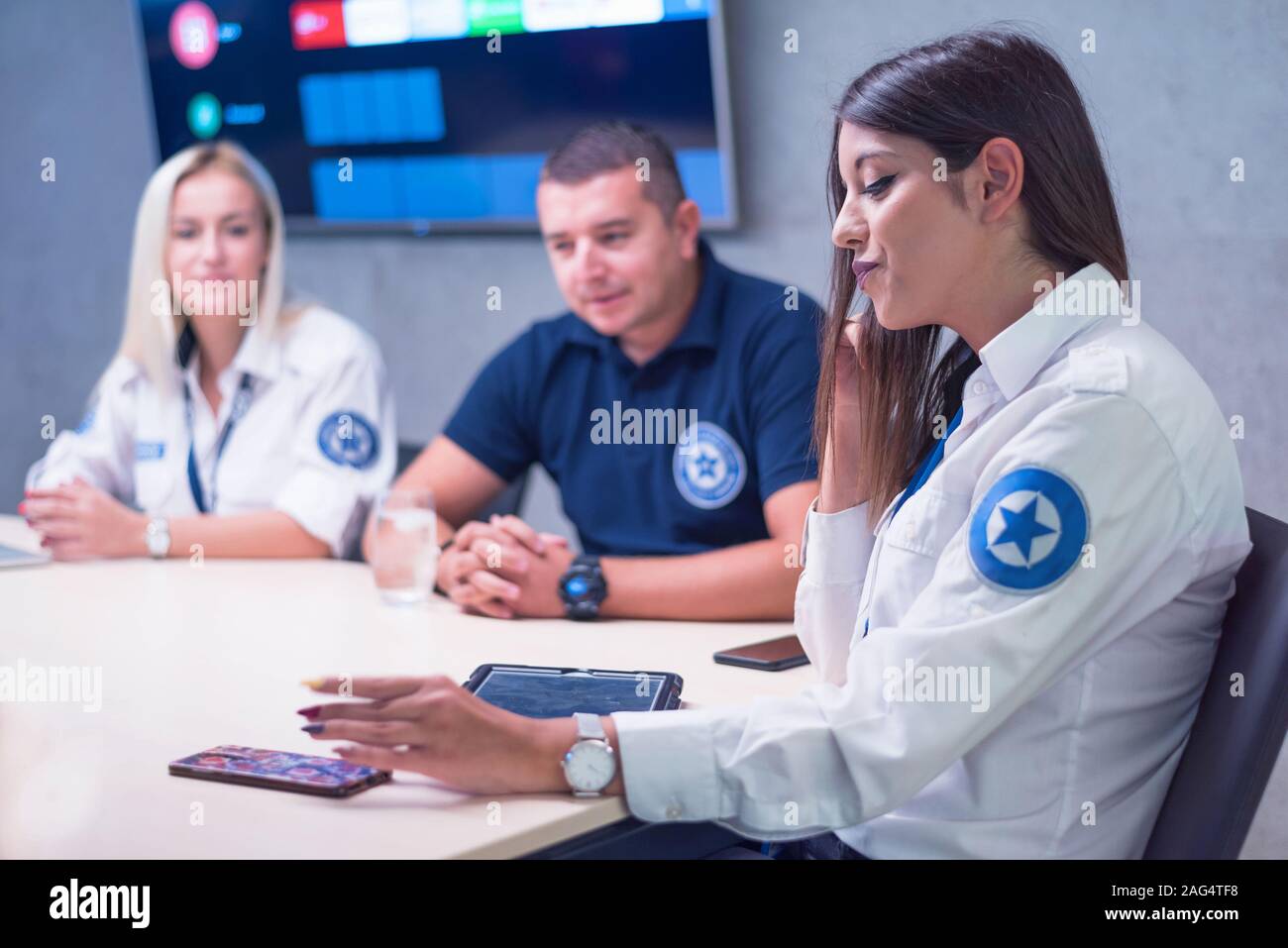 Group of security guards working on computers while sitting in the main ...