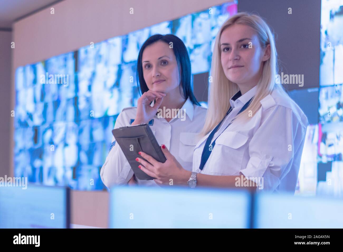 Two security guards working on computers while sitting in the main ...