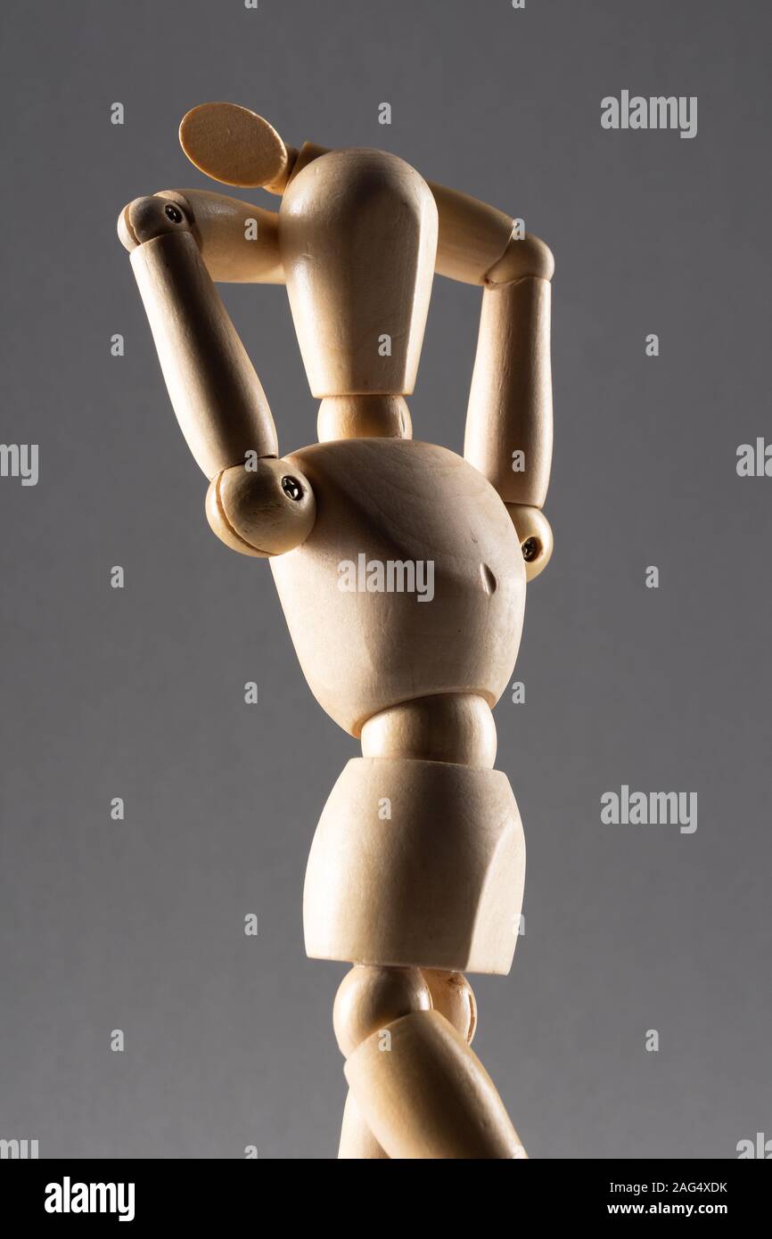 Vertical closeup shot of a wooden pose doll with both hands behind its ...