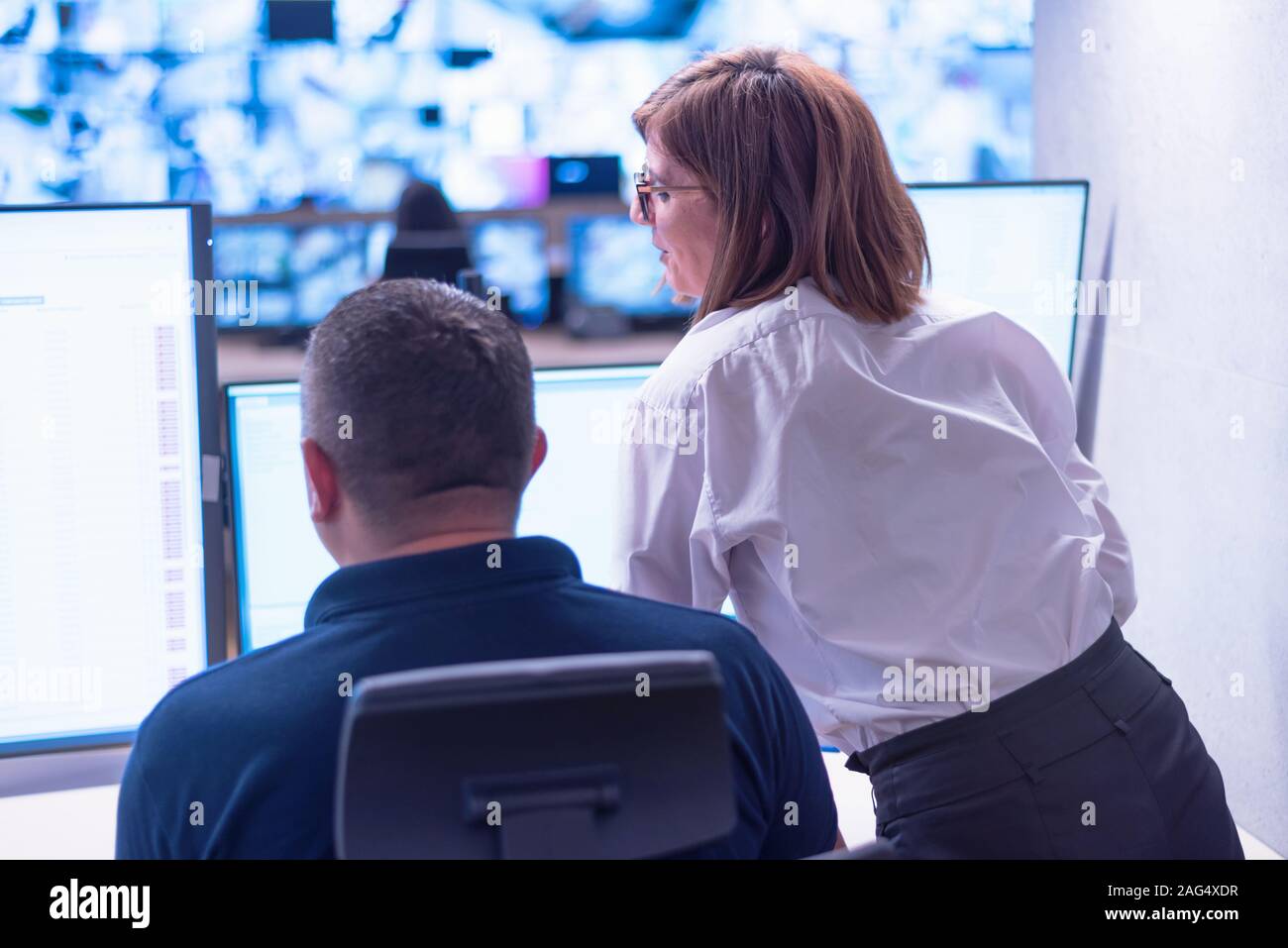 Two security guards working on computers while sitting in the main ...