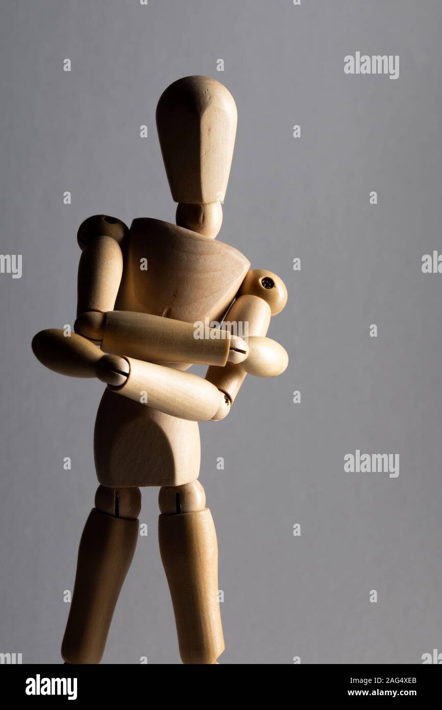 Vertical closeup shot of a wooden pose doll with crossed arms standing ...