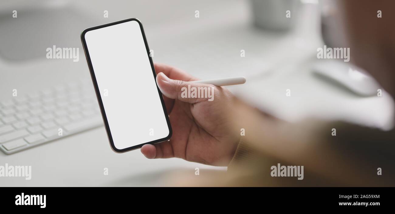 Close-up view of young man holding smartphone in modern office room ...