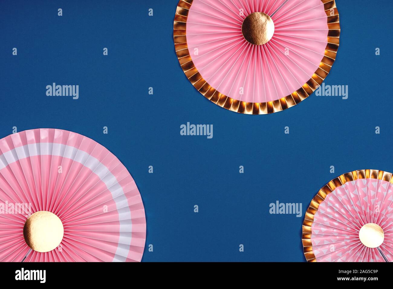 Pink and golden paper fans on classic blue. Party decorations ...