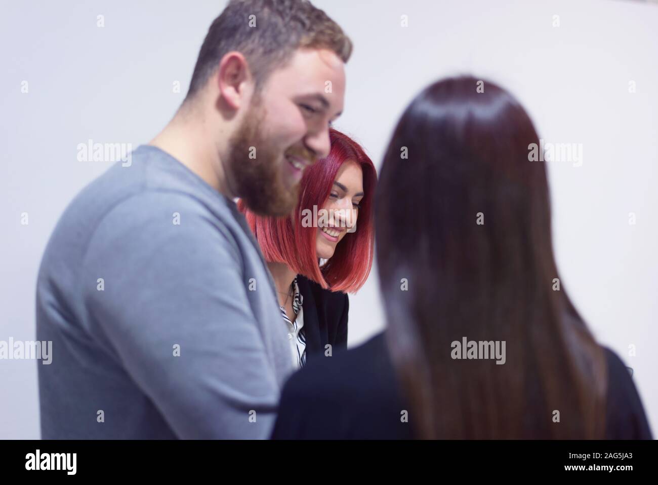 Three college students standing in corridor and chatting after their ...