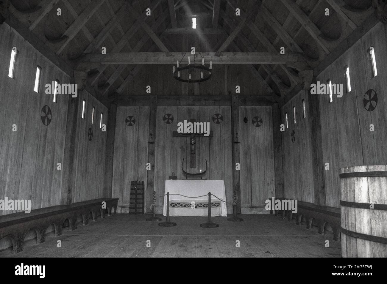 Grayscale shot of the inside of a wooden chapel in a Viking village ...