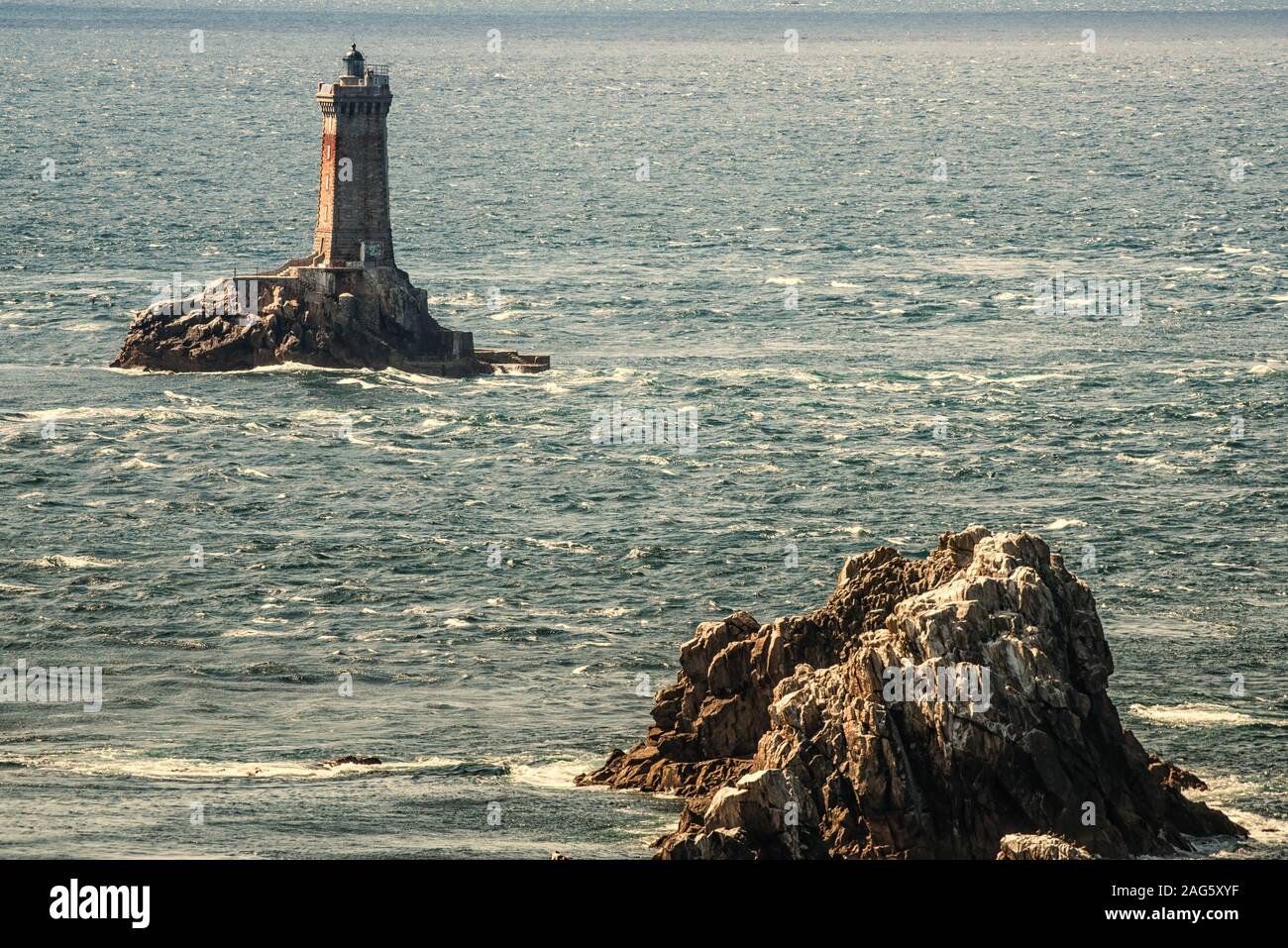 Concrete lighthouse on a rock formation in the middle of the sea during ...