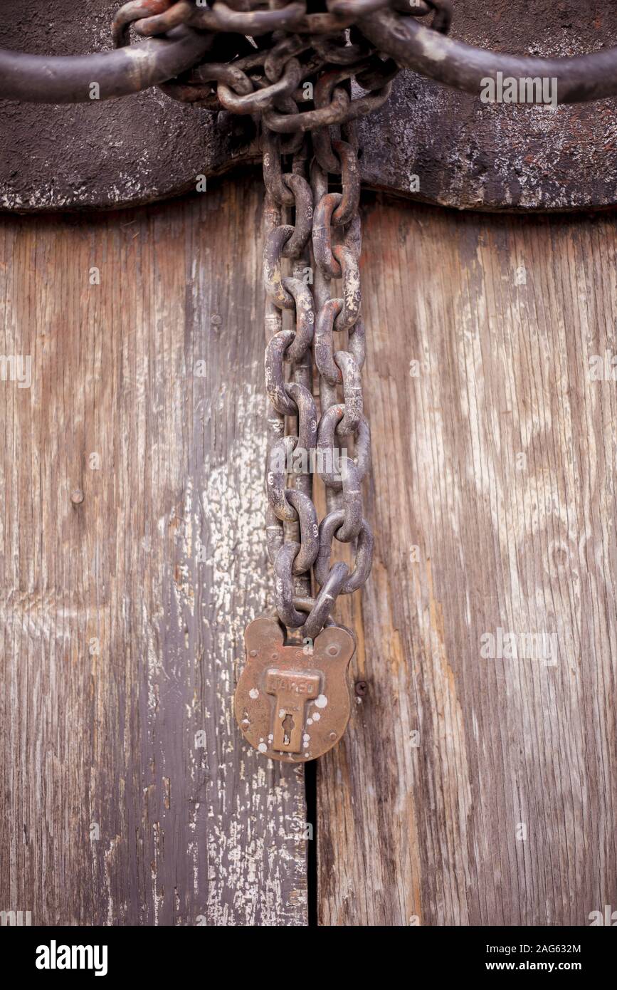 Vertical closeup shot of an old wooden gate with a rust iron lock and ...