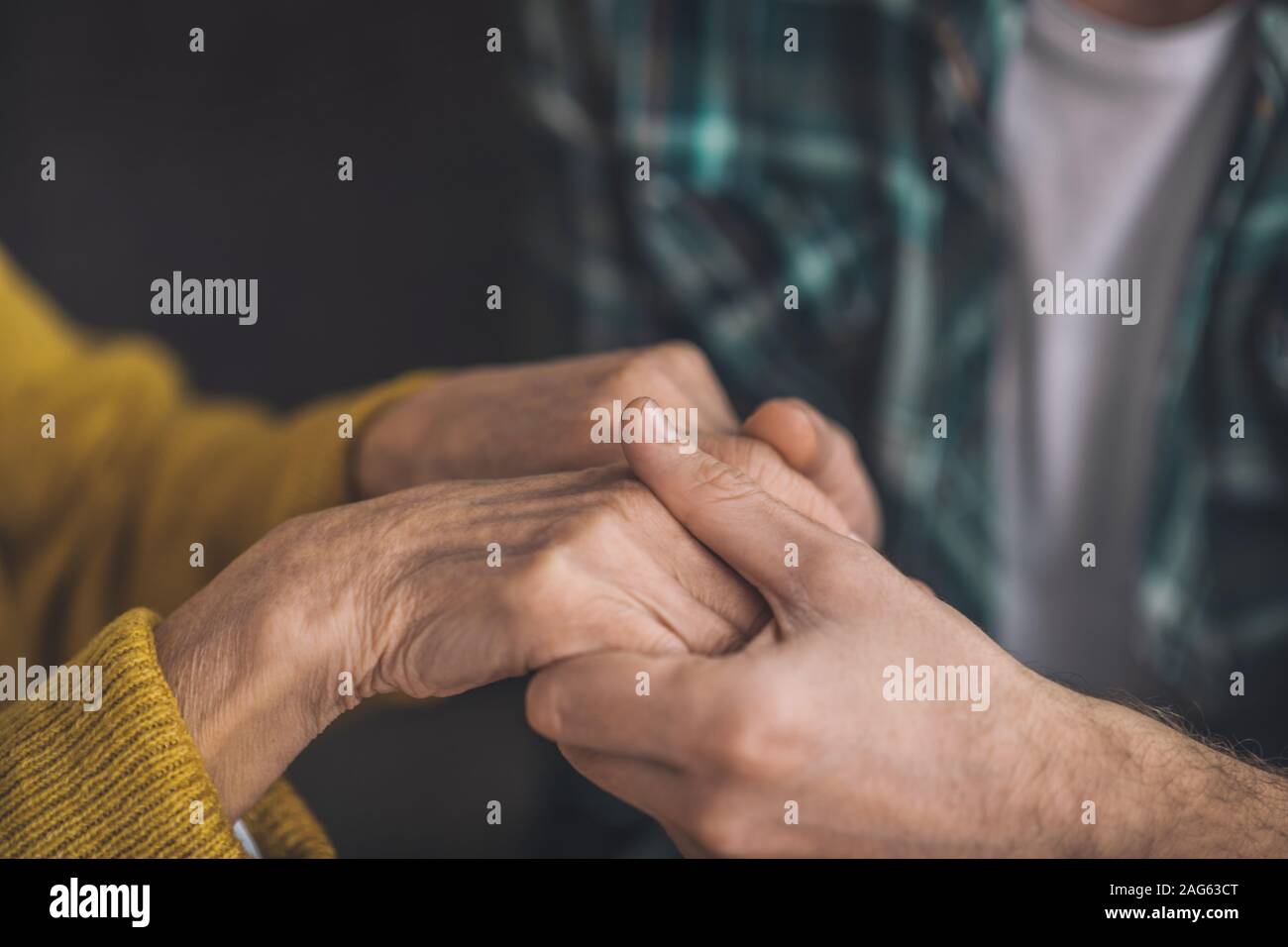 Loving son. Young man tenderly holding his moms hands Stock Photo - Alamy
