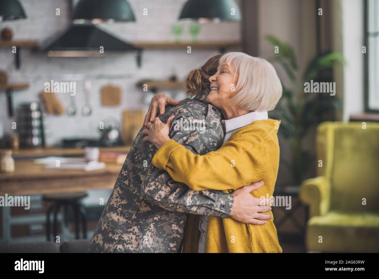 Visiting mom. Mom in yellow shirt hugging her son in uniform Stock ...