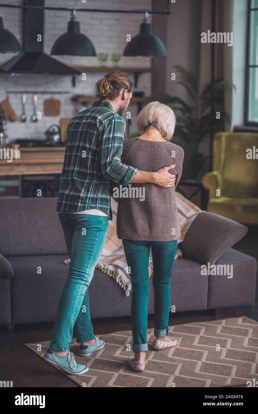 Sons support. Young man in jeans supporting his mom Stock Photo - Alamy