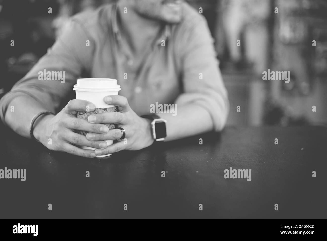Closeup shot of a male holding his coffee while sitting with blurred ...