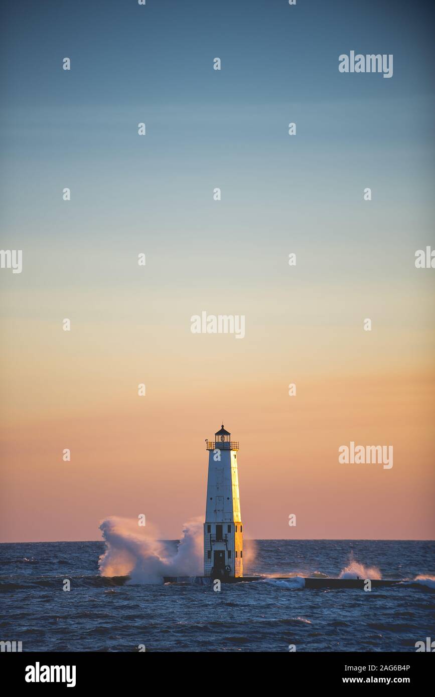 Vertical shot of a lighthouse in the sea with the waves hitting the ...