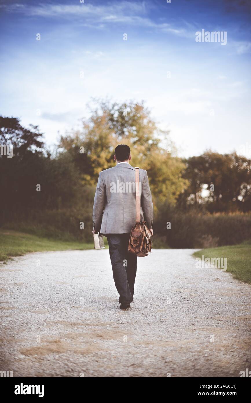 Vertical shot from behind of a businessman walking on a pathway while ...