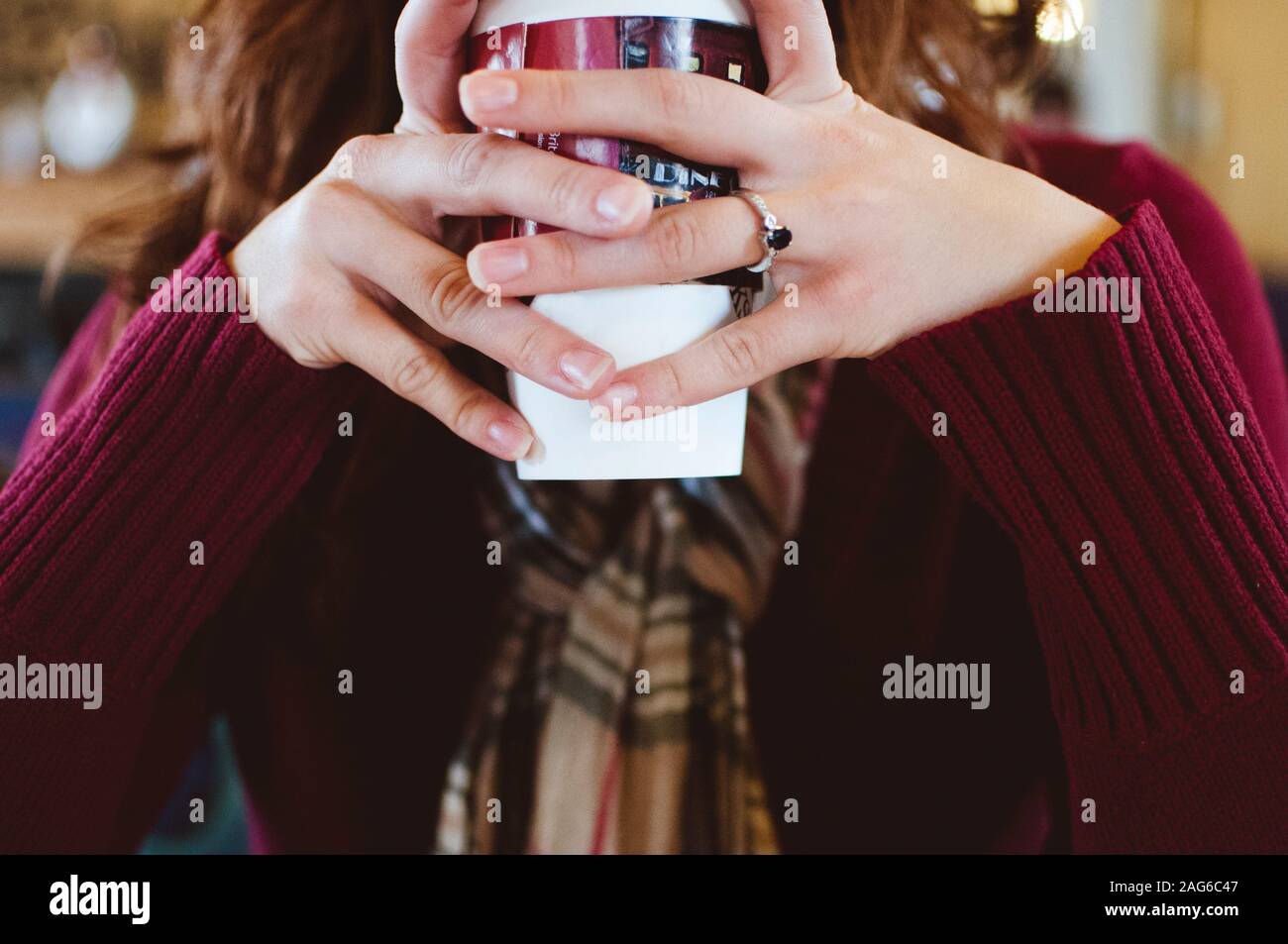 Closeup shot of a female drinking her coffee with two hands with a ...