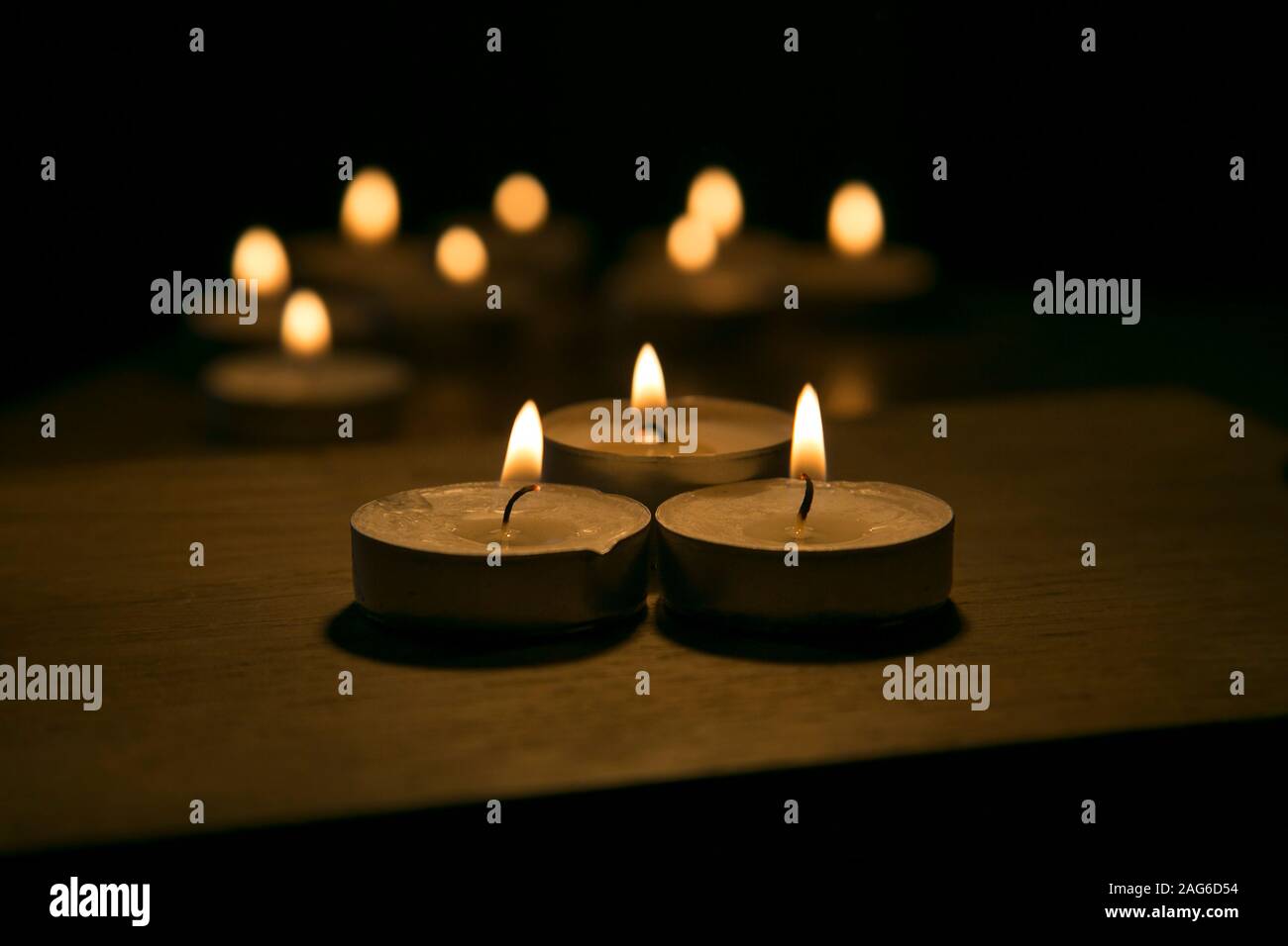 An arrangement of burning tea lights in a darkened space Stock Photo ...