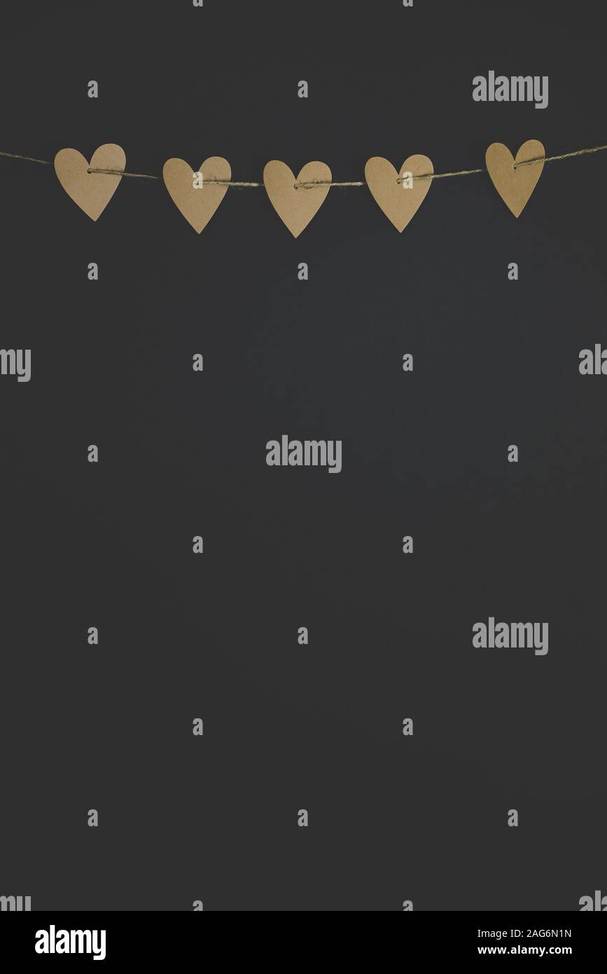 Vertical shot of heart-shaped cut-outs on a string with a black ...