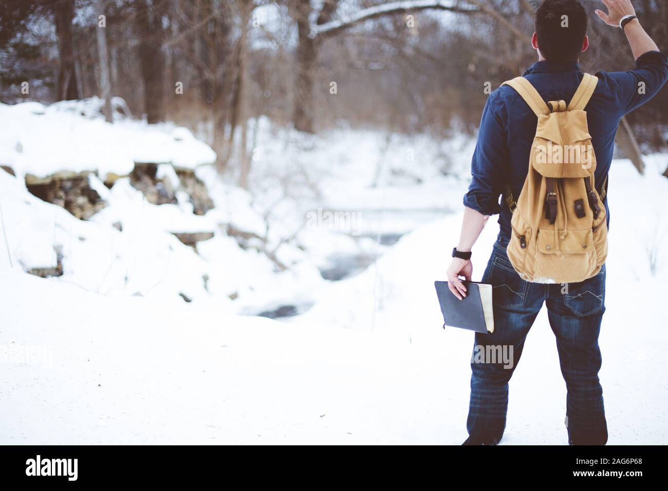 Closeup shot from behind of a male wearing a yellow backpack and waving ...