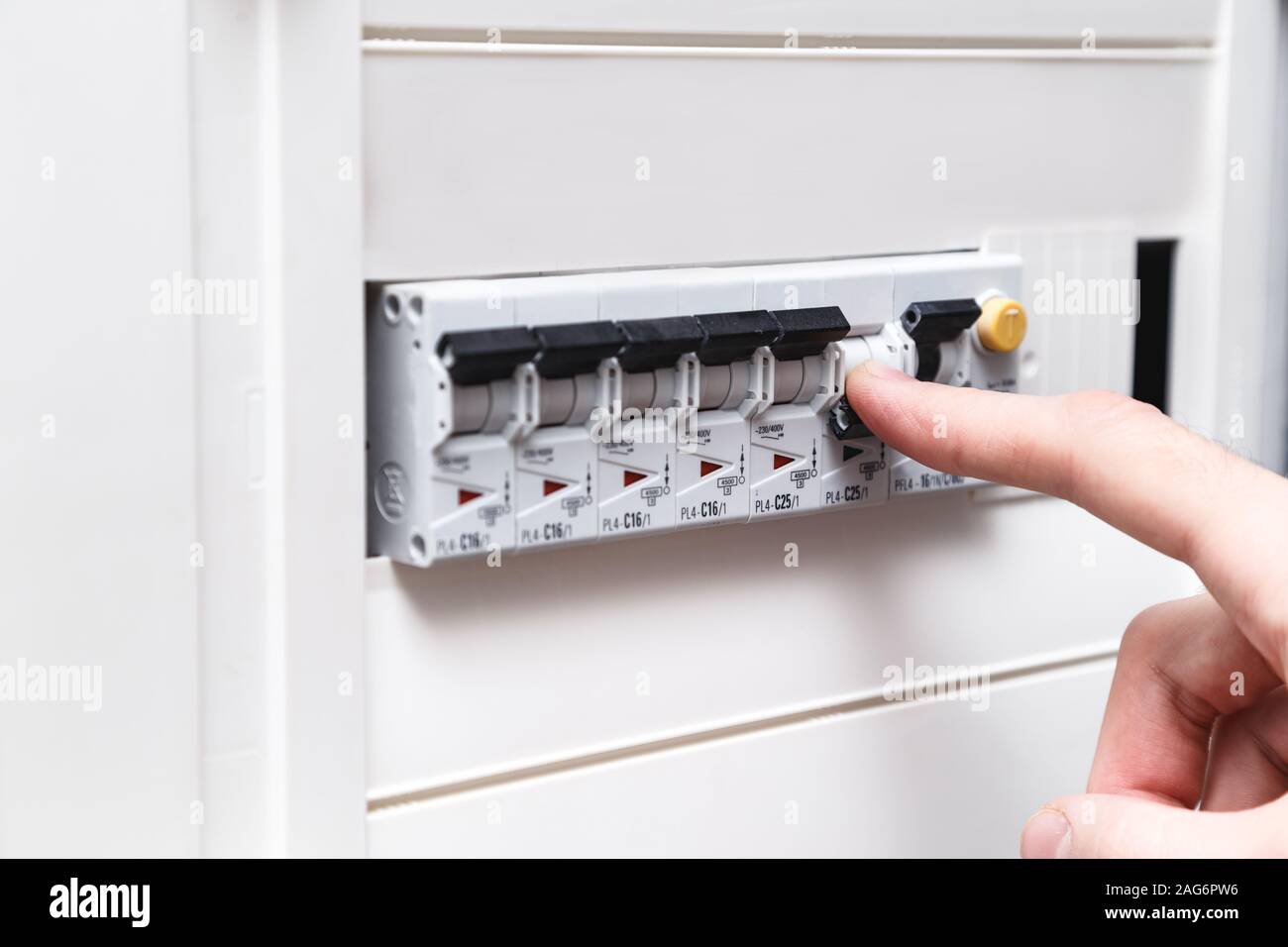 An RCD circuit breaker board with many switches. Man's hand is about ...
