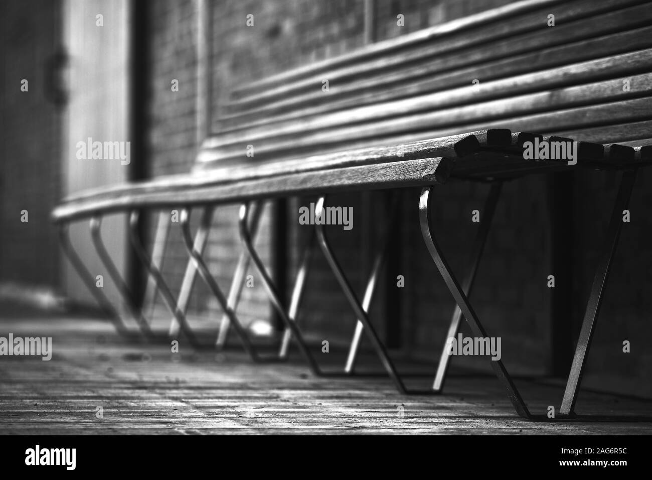 Grayscale low angle shot of a wooden bench in the station in an urban ...