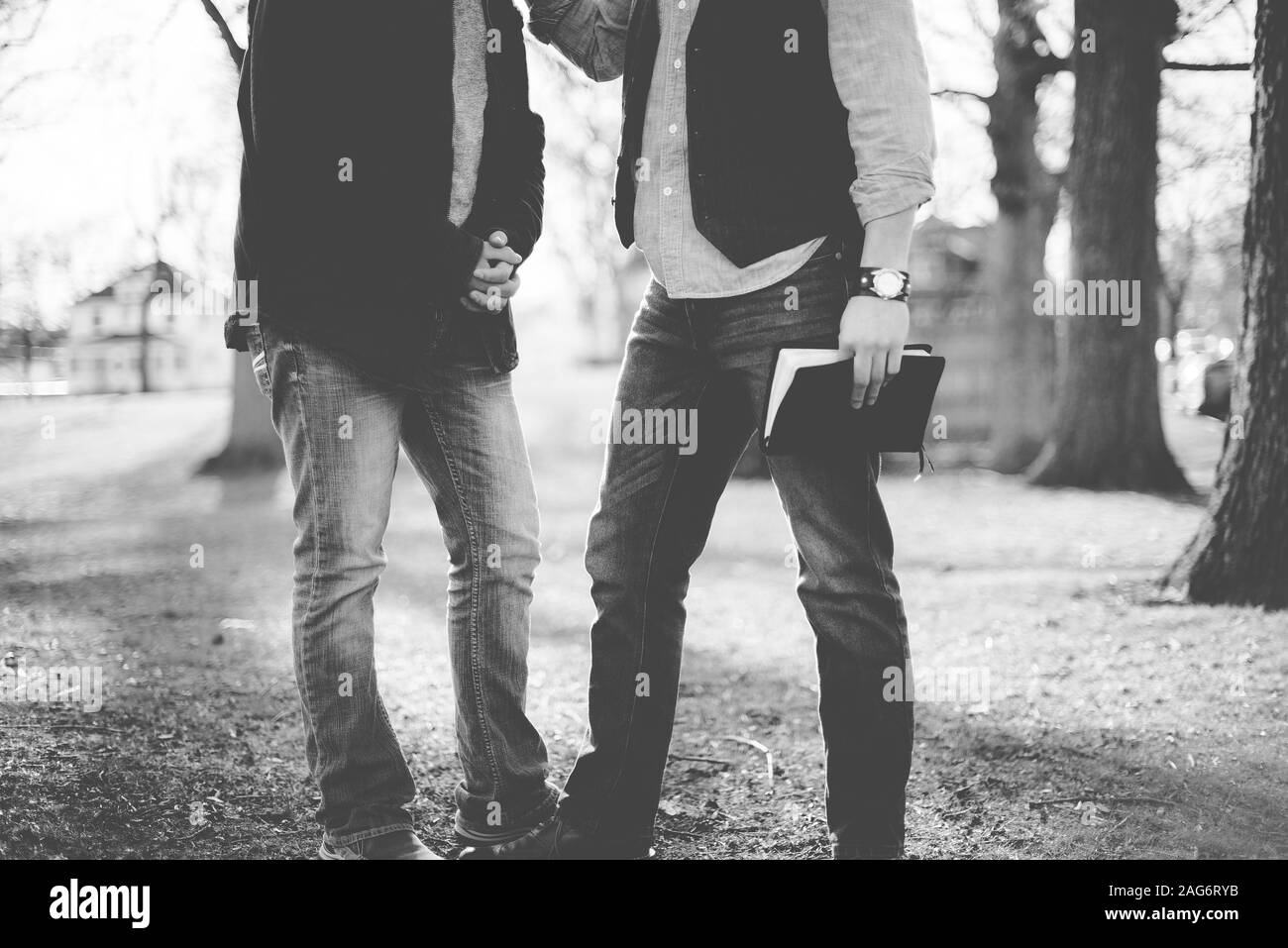 Grayscale shot of two males talking to each other while holding the ...