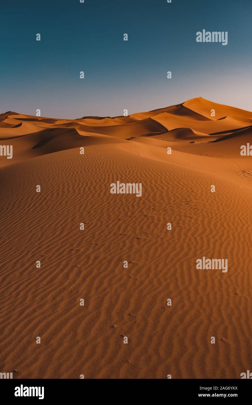 Vertical shot of a peaceful desert under the clear blue sky captured in ...