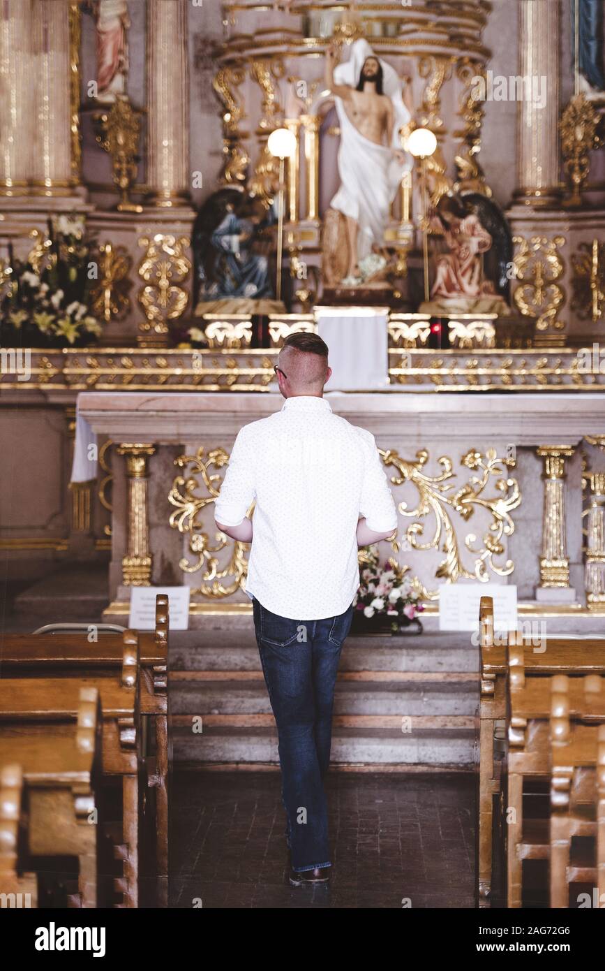 Vertical shot of a male standing in the church and praying with a ...