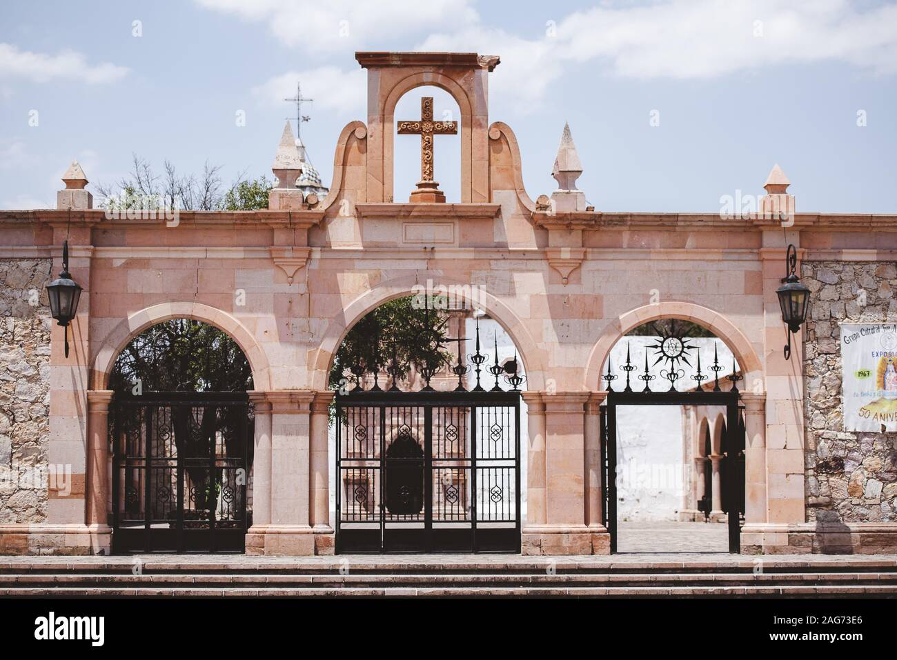 Beautiful shot of church walls with a metal gate and a cross on top ...