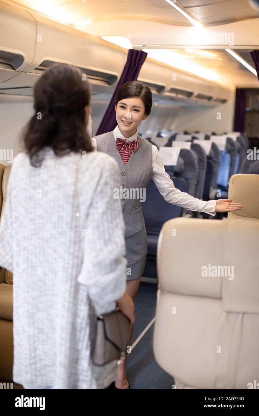 Chinese flight attendant showing seats on plane Stock Photo - Alamy