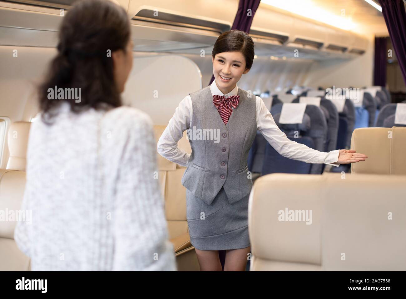 Chinese flight attendant showing seats on plane Stock Photo - Alamy